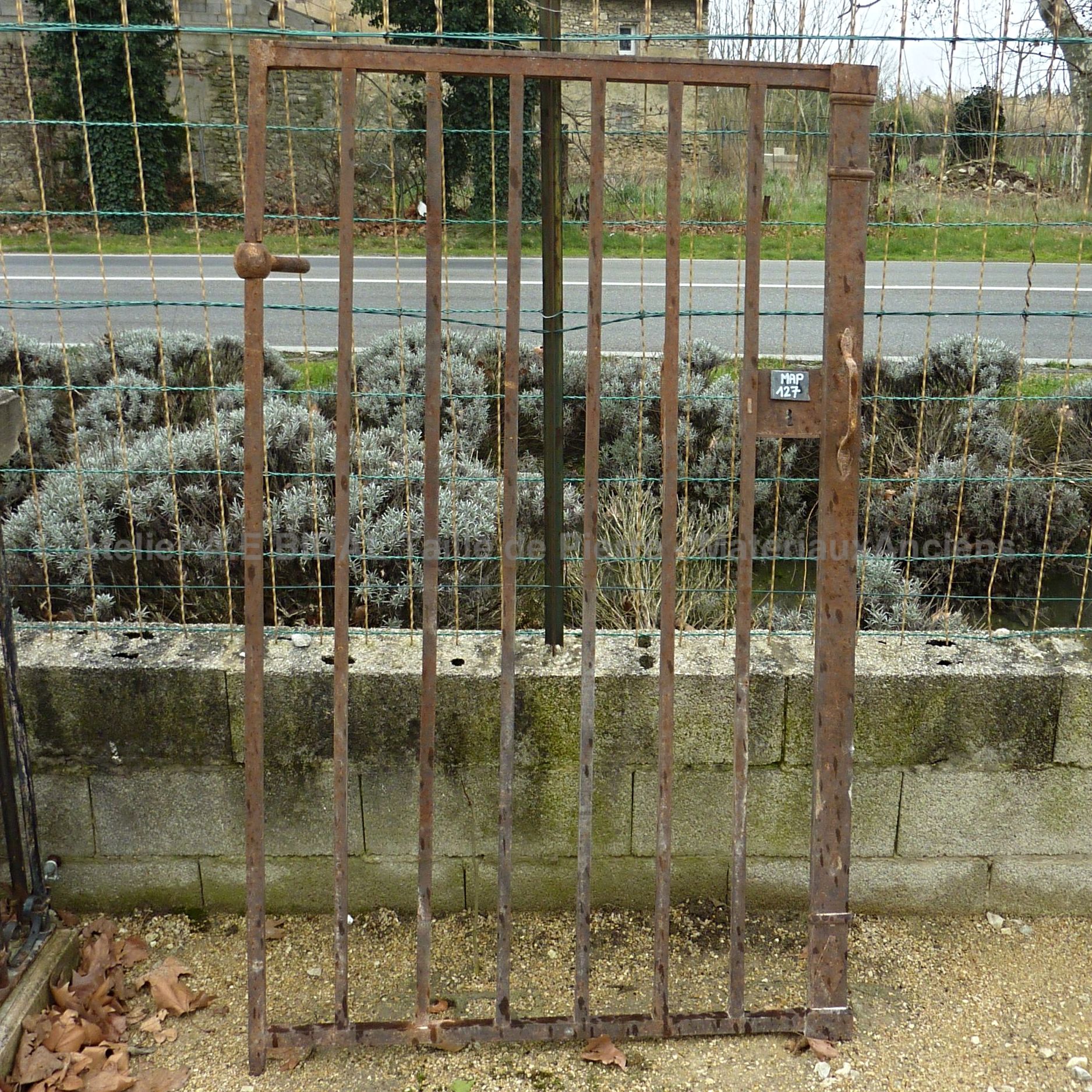Un petit portillon ancien - porte en fer forgé ajouré, style rustique.