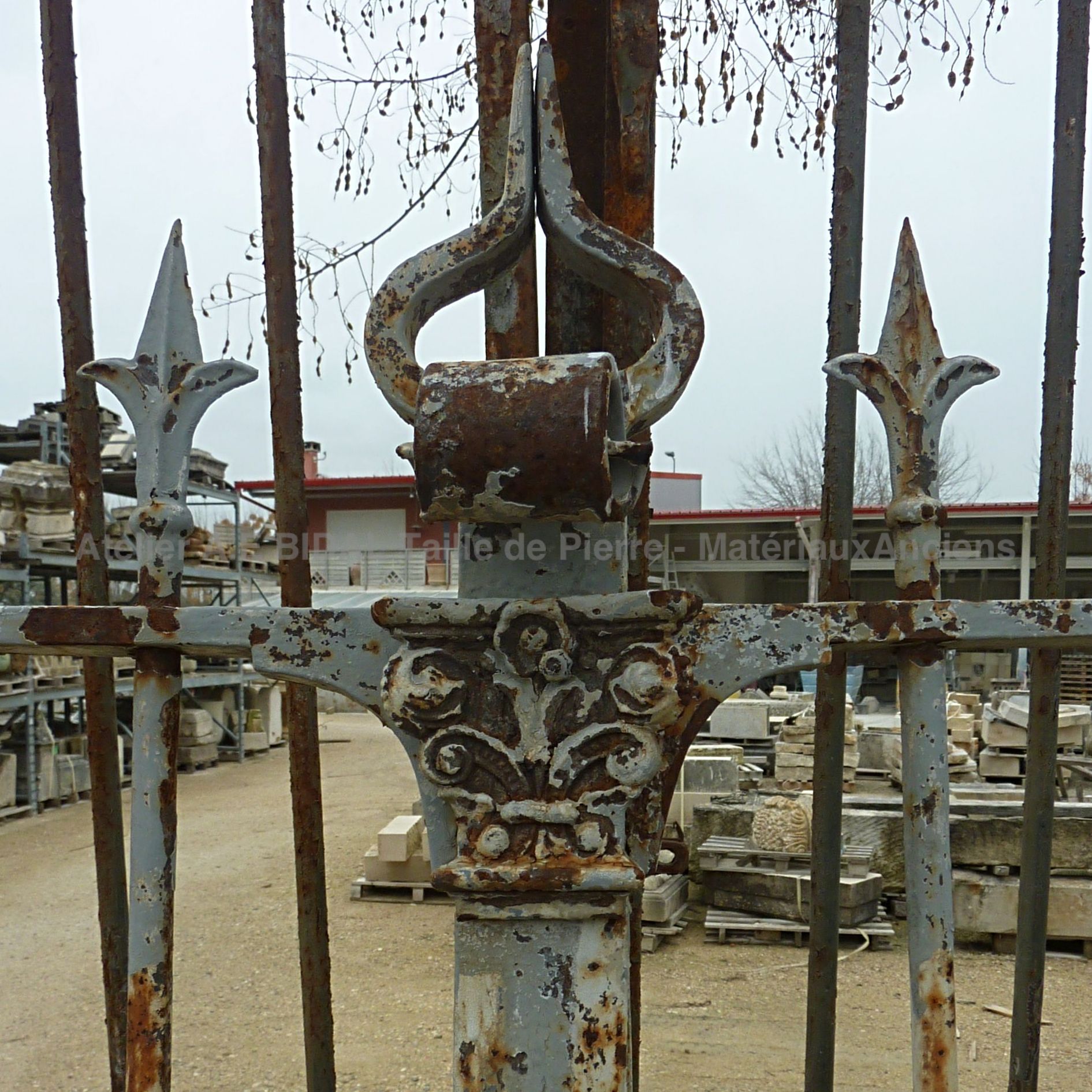 Antique riveted wrought-iron gate with two semi-openwork doors.